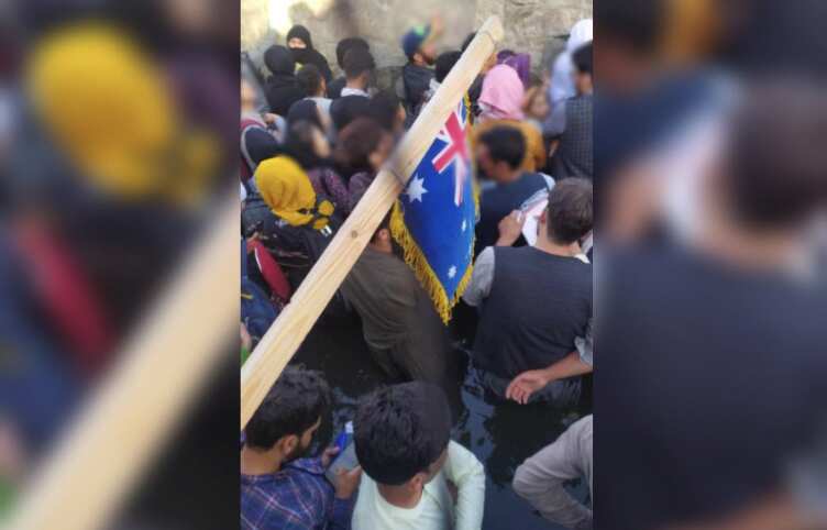 Afghans with Australian flag wade through sewage at Kabul airport as ...